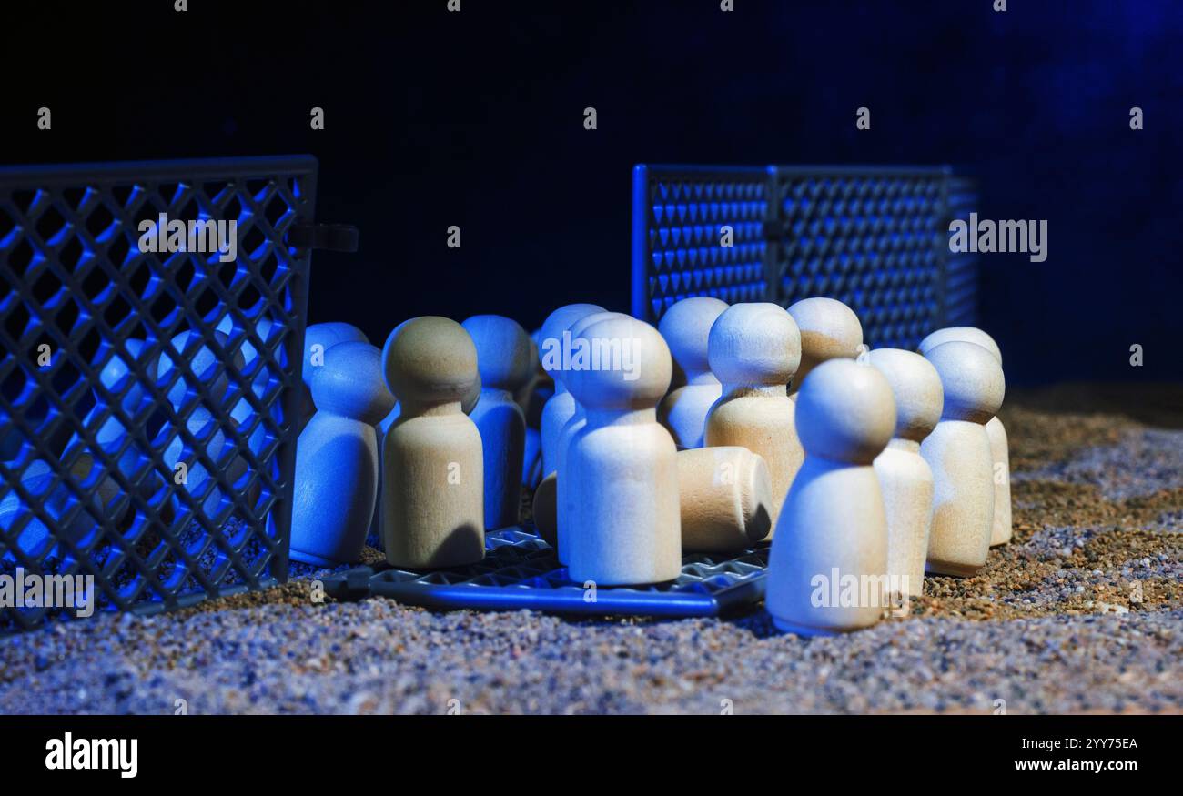 Wooden figures behind a symbolic border fence at night Stock Photo - Alamy