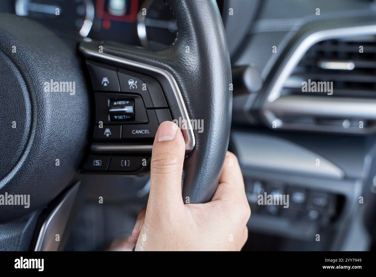 Woman's hand presses the button on the steering wheel of the car close ...