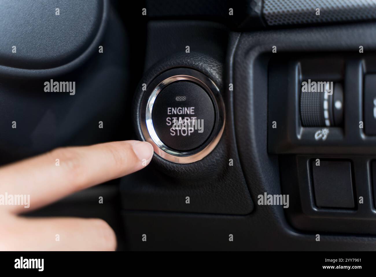 Woman finger pressing the start/stop engine button on car. Close up of ...