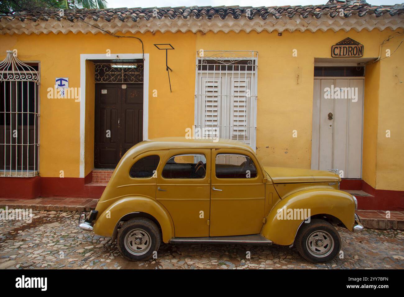 A Vintage yellow Ford car in front of a typical yellow colonial house ...