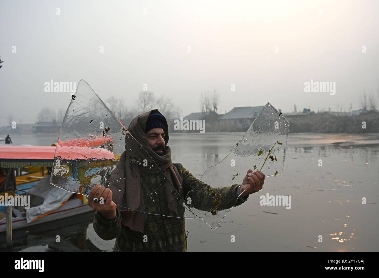 SRINAGAR, INDIA - DECEMBER 19: A man shows ice sheets of partially ...