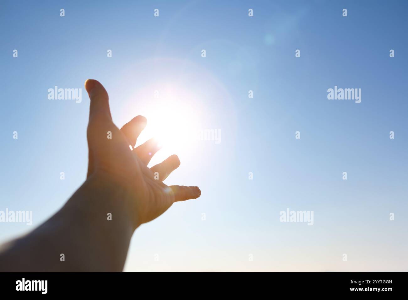 Strong rays of light shining between hands stretched out toward the ...
