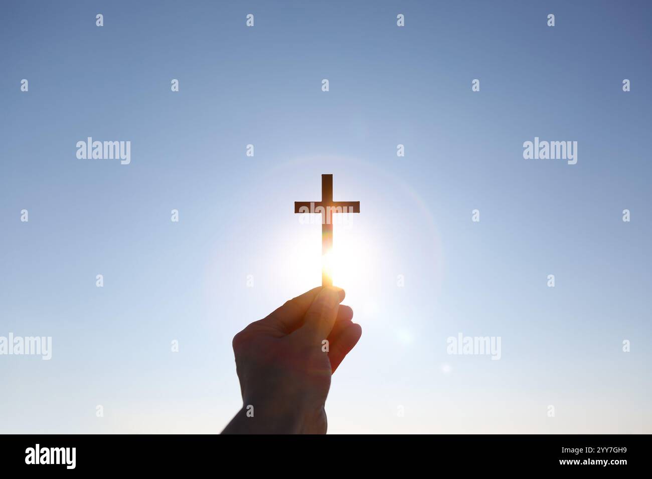Lifting the cross of Jesus Christ toward the bright sunrise sunlight ...