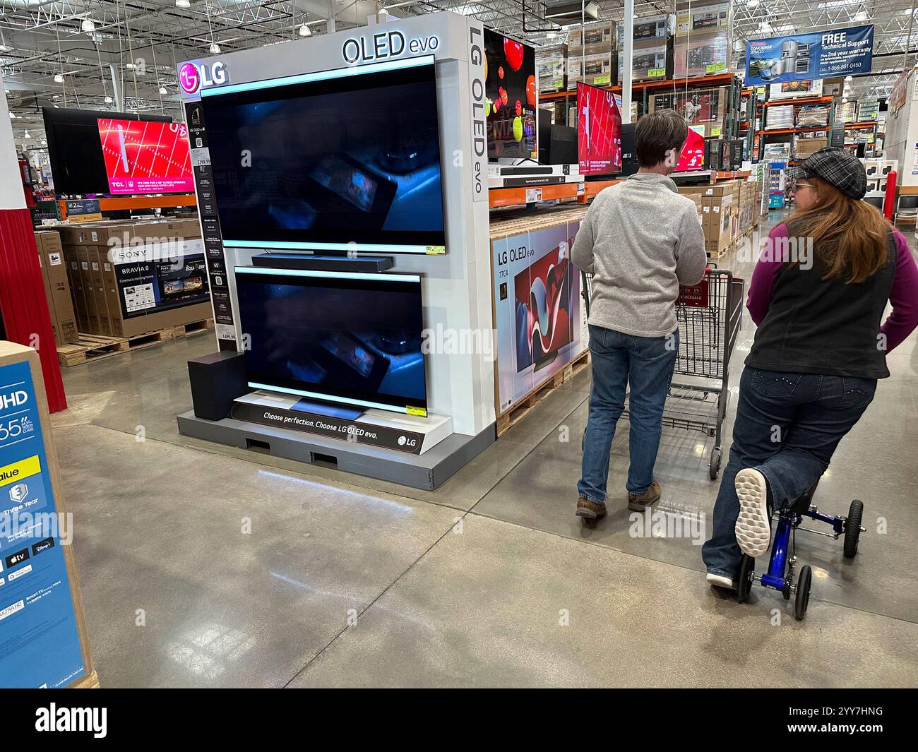 Shoppers pass by a display of big-screen televisions in a Costco ...