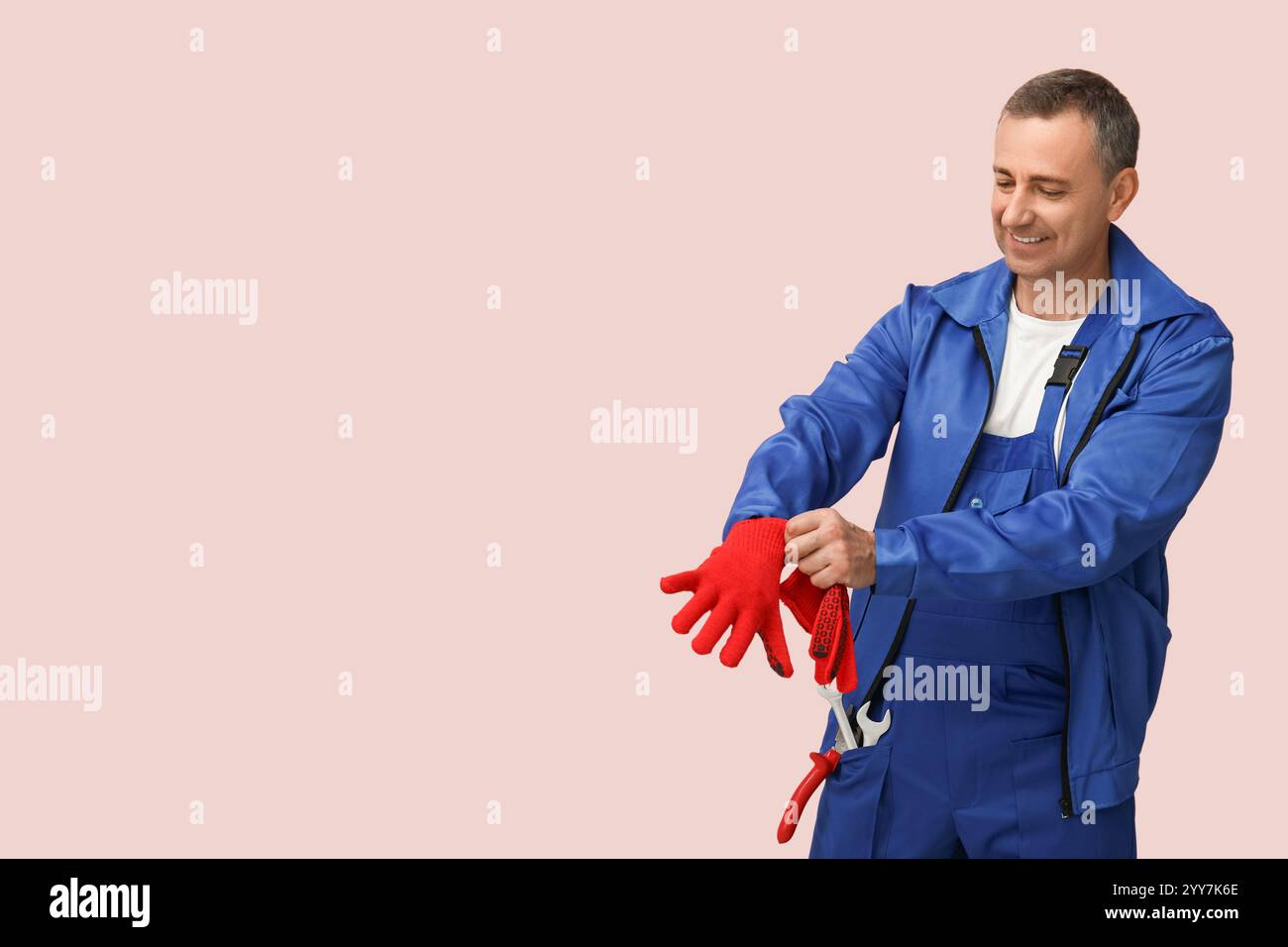 Portrait of male mechanic with gloves on pink background Stock Photo ...