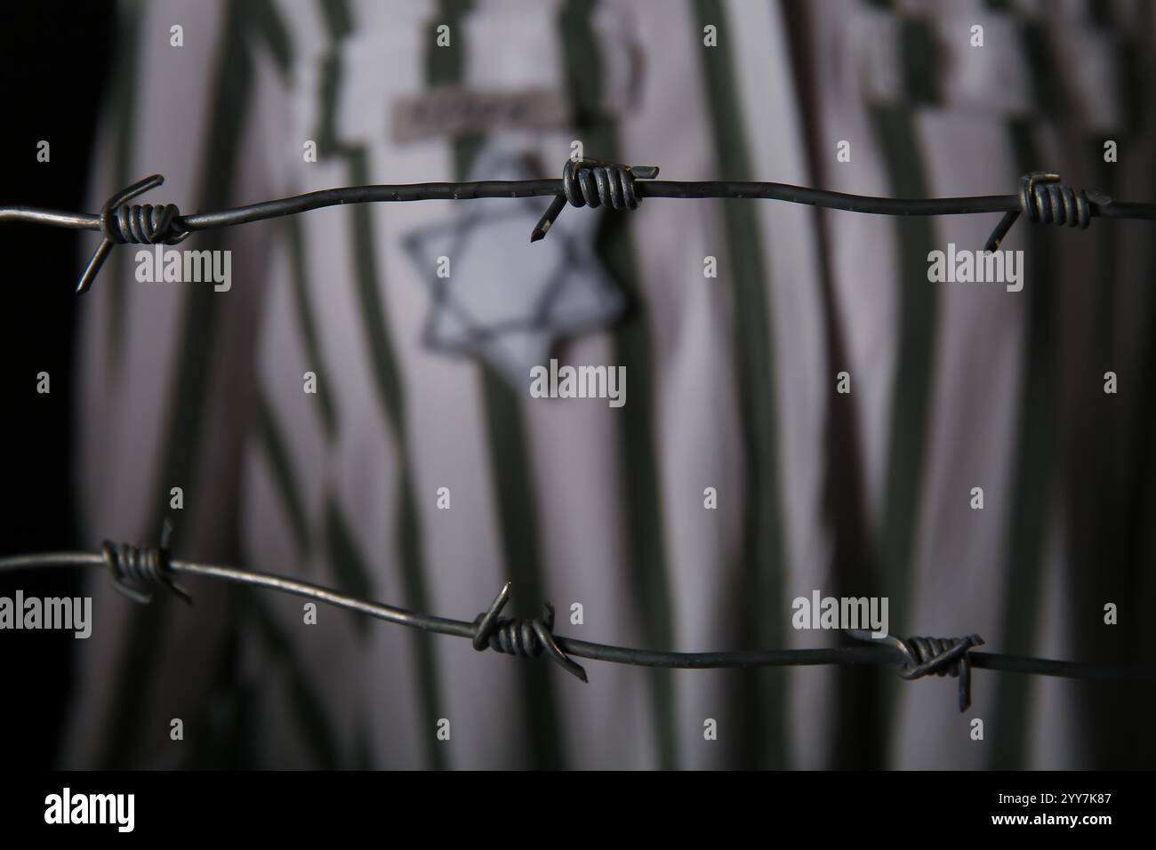 Jewish female prisoner behind barbed wire on dark background, closeup ...