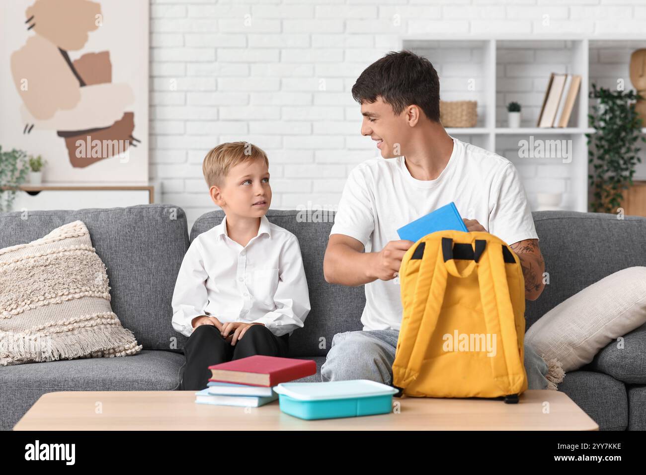 Father and his little son packing books into backpack at home Stock ...