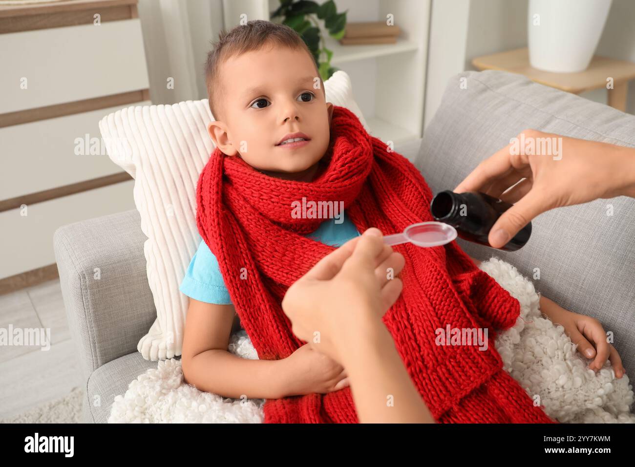 Sick little boy with his mother pouring couch syrup at home Stock Photo ...