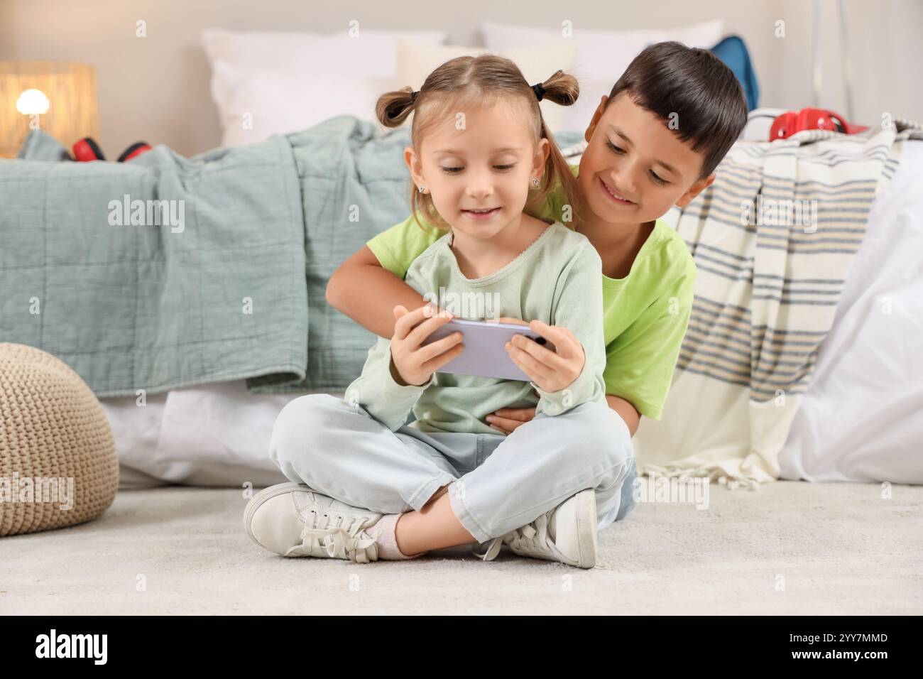 Cute happy little kids with mobile phone playing video games on floor ...