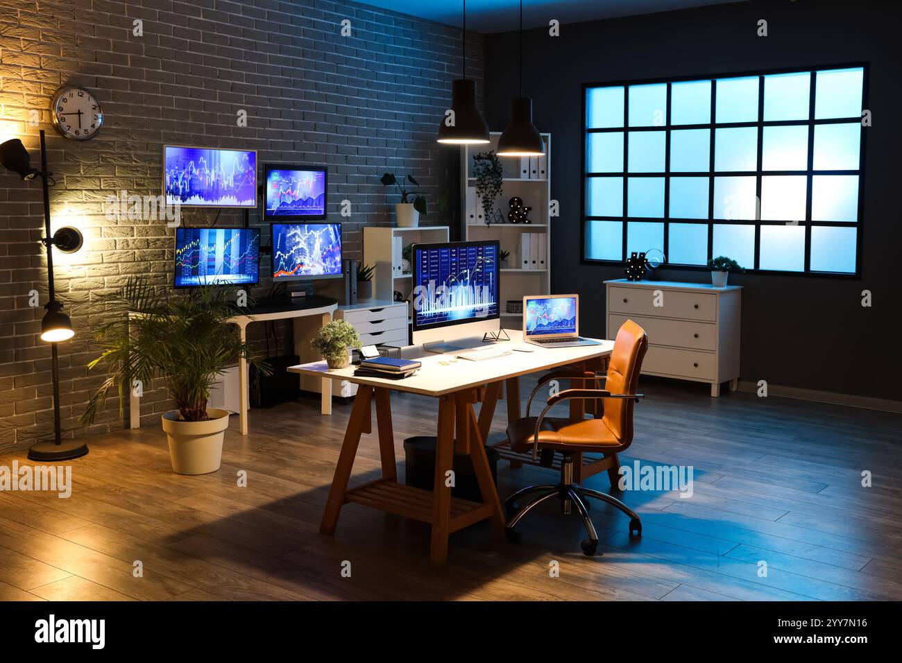Interior of dark office with trader's desks and glowing lamps at night ...