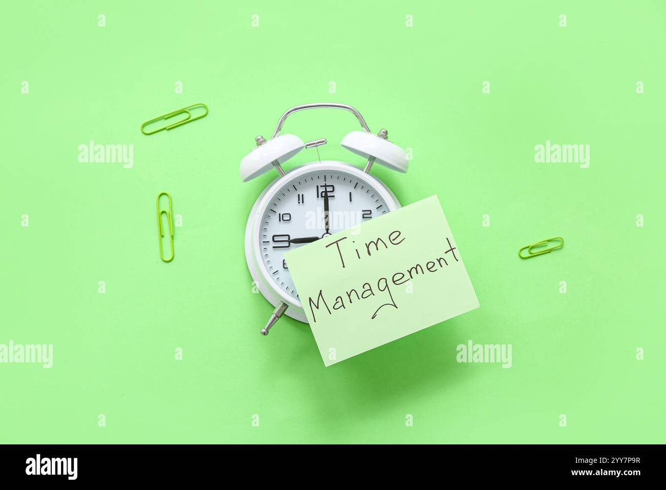 Sticky note with text TIME MANAGEMENT, alarm clock and paper clips on ...