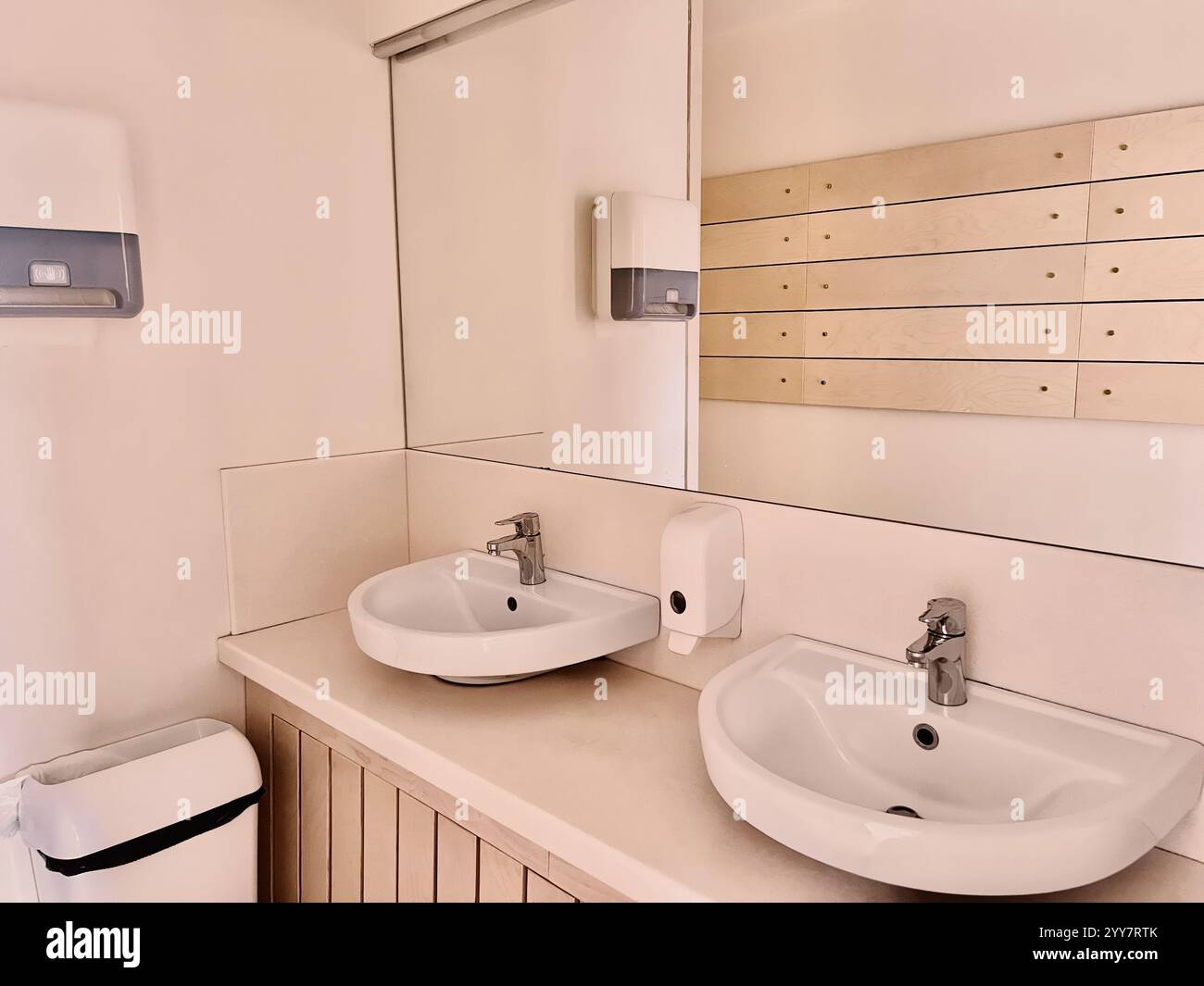 single sink in small public toilet with wall soap dispenser and paper ...