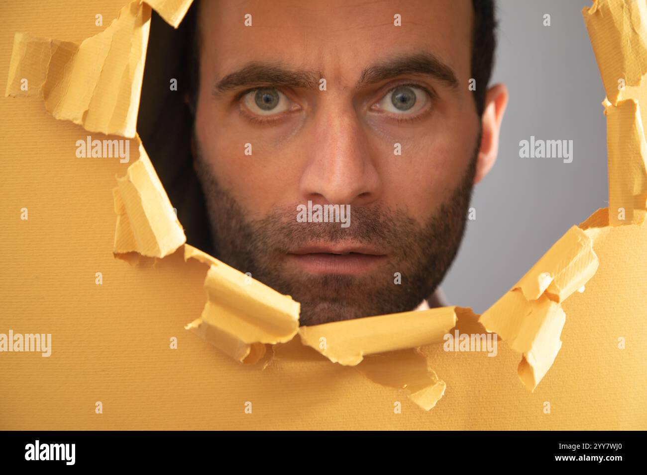 Man looking through hole in paper Stock Photo - Alamy