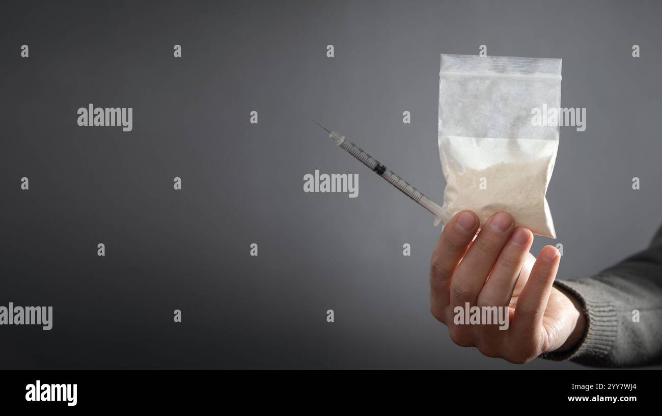 Male hand showing syringe and plastic packet of heroin Stock Photo - Alamy