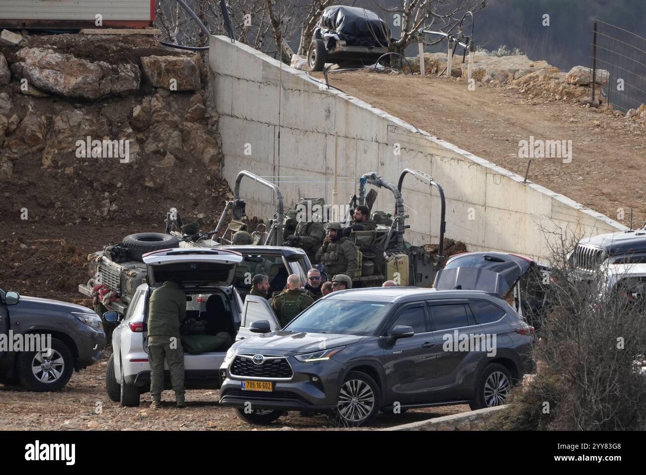 Israeli soldiers stand next to an army vehicle before crossing the ...