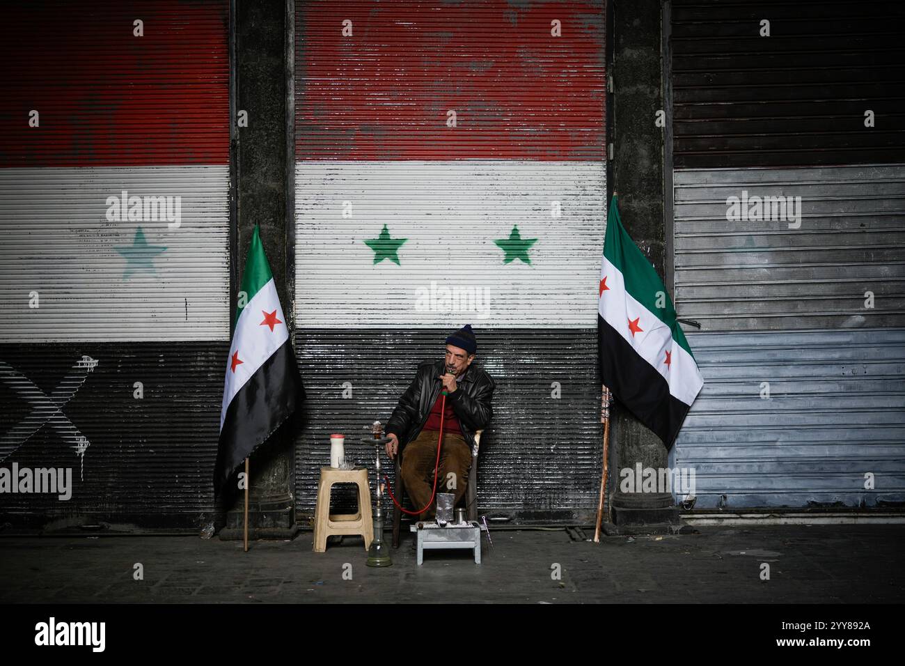 A man smokes a water pipe next to two Syrian "revolutionary" flags in ...