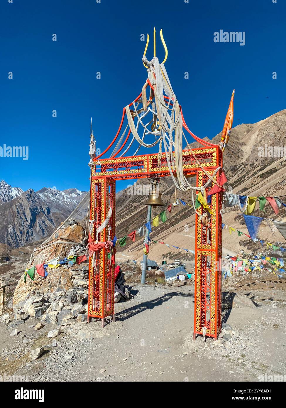 Sacred gate with flags and temple bell on the road leading to Om Parvat ...