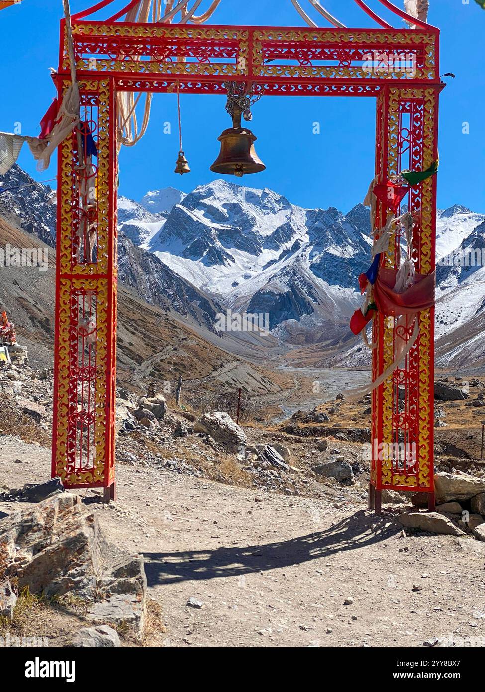 Sacred gate with flags and temple bell on the road leading to Om Parvat ...