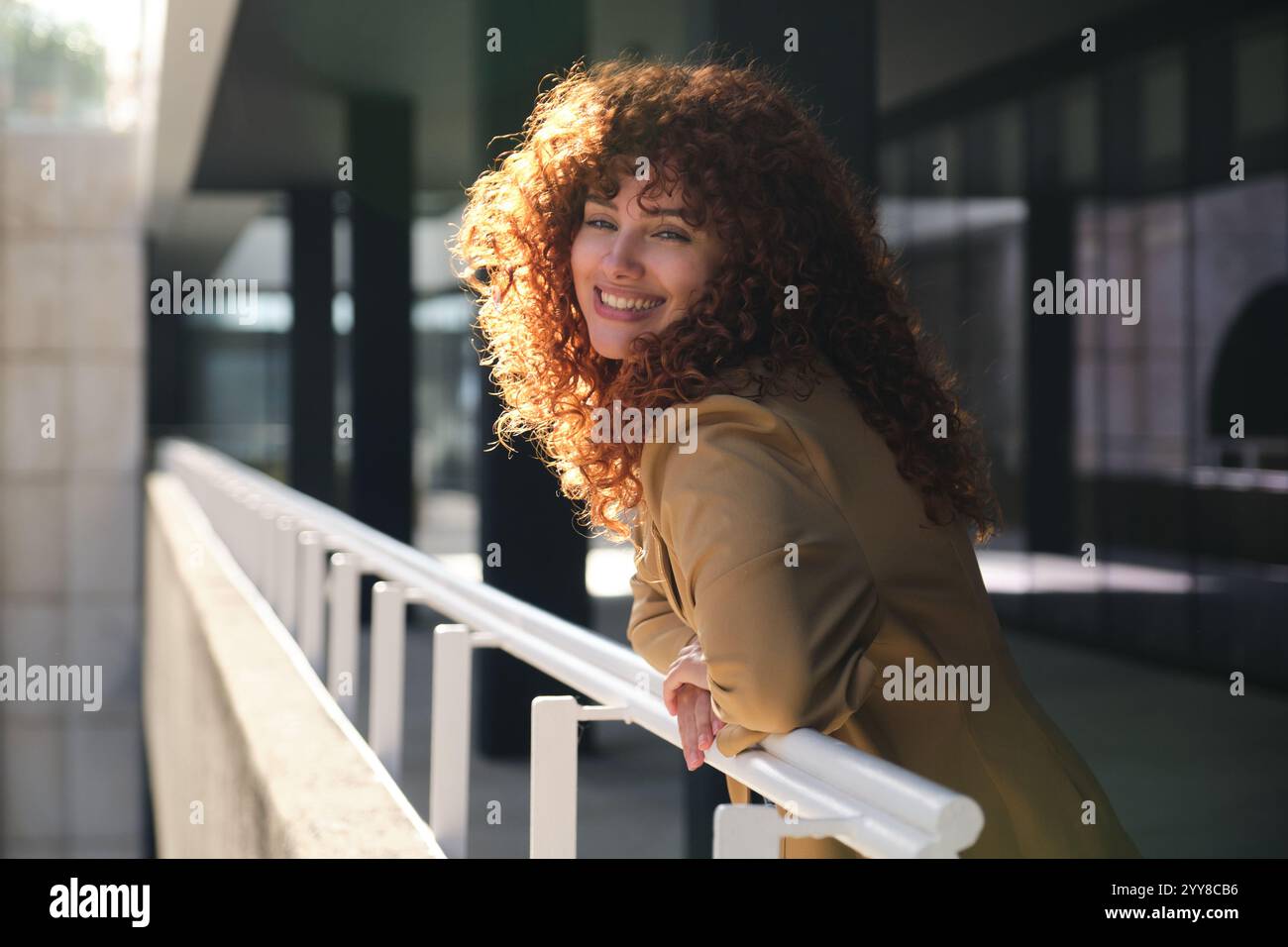 Smiling businesswoman leaning on railing outside office building Stock ...