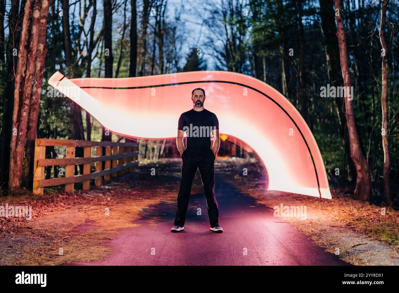 Man standing on a forest path with light painting effect behind Stock ...
