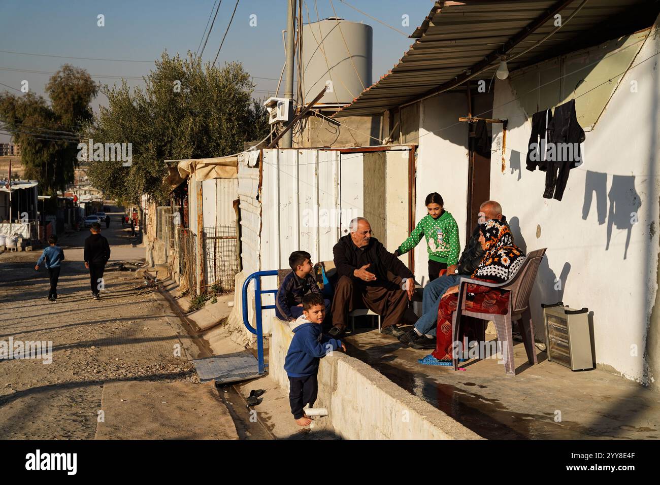 People stand in front of the house at Domiz camp for Syrian Kurdish ...