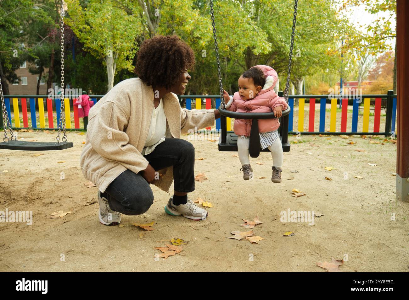Mother pushing her baby daughter on a swing in a playground Stock Photo - Alamy