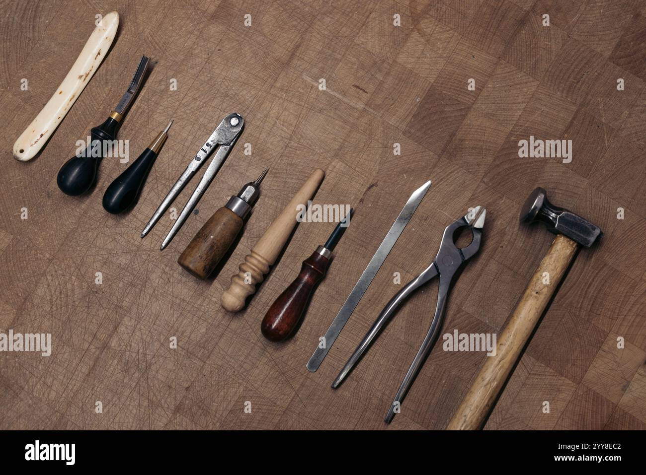 Leather crafting tools neatly arranged on wooden workbench Stock Photo ...