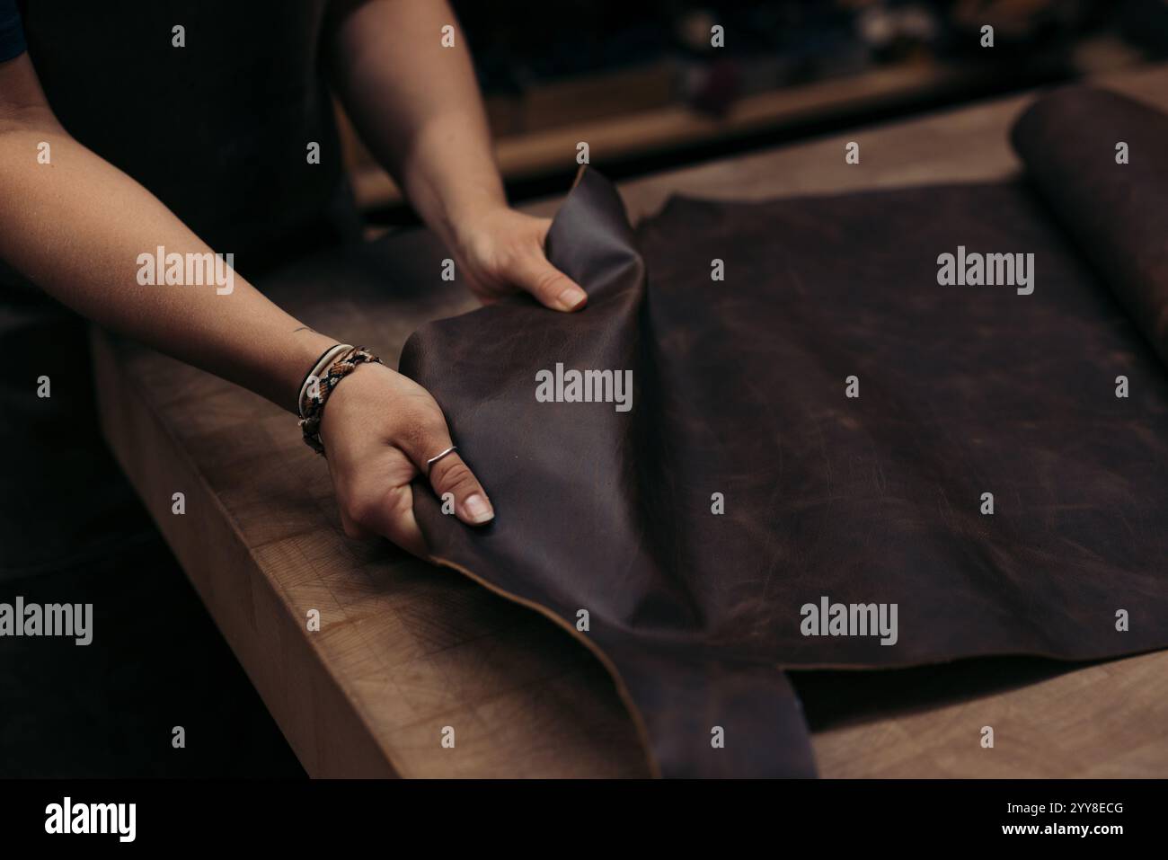 Artisan handling rich brown leather sheet for tailoring crafts Stock ...
