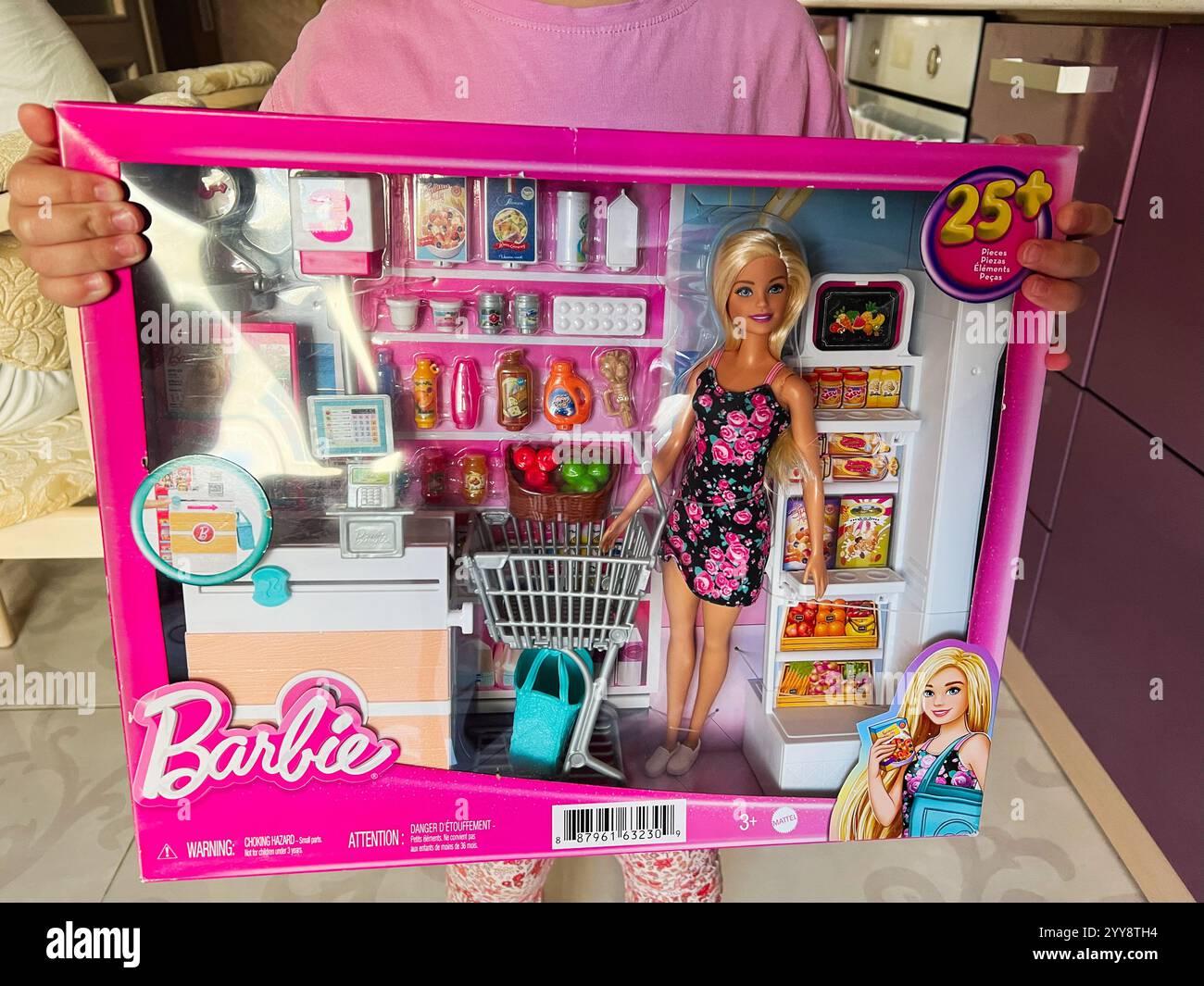 Child showcasing a Barbie-themed toy package including a miniature ...
