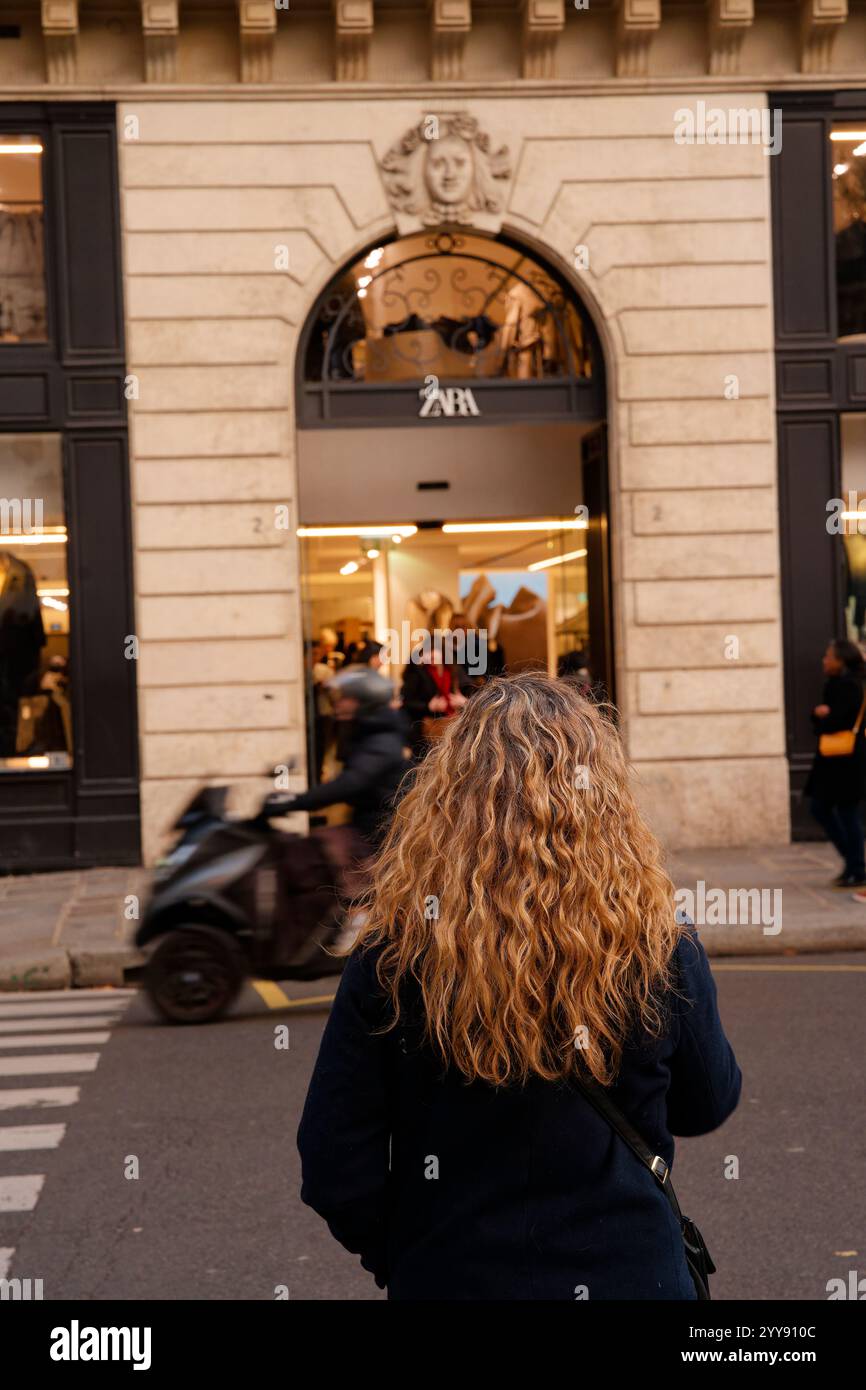 Woman with curly hair observes a fashion store in a bustling urban ...