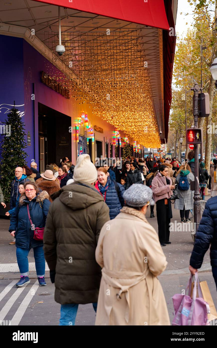 Crowd of people enjoying a festive street decorated with bright lights ...