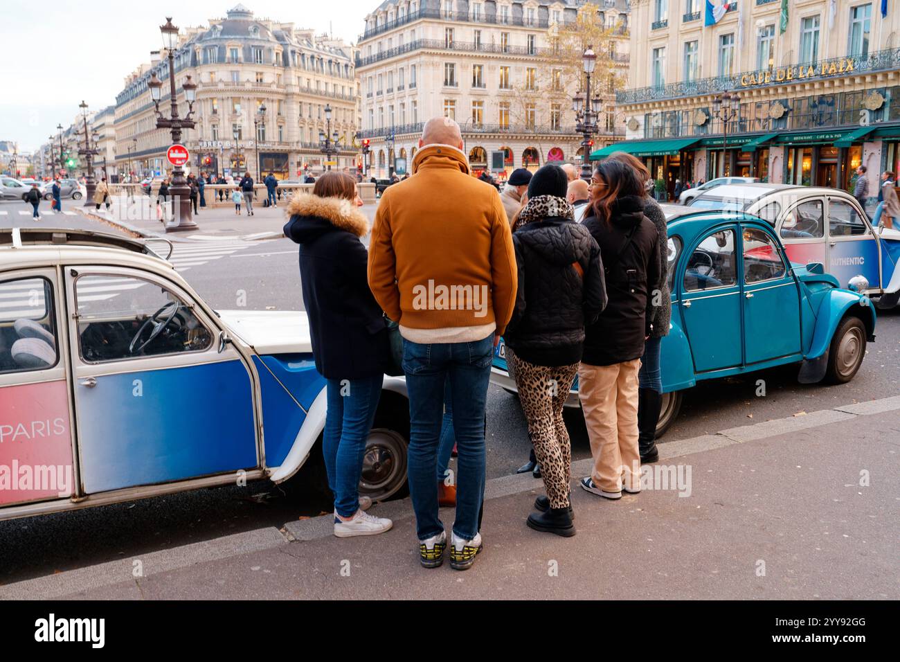 Group of friends gathered around classic cars while enjoying a lively ...