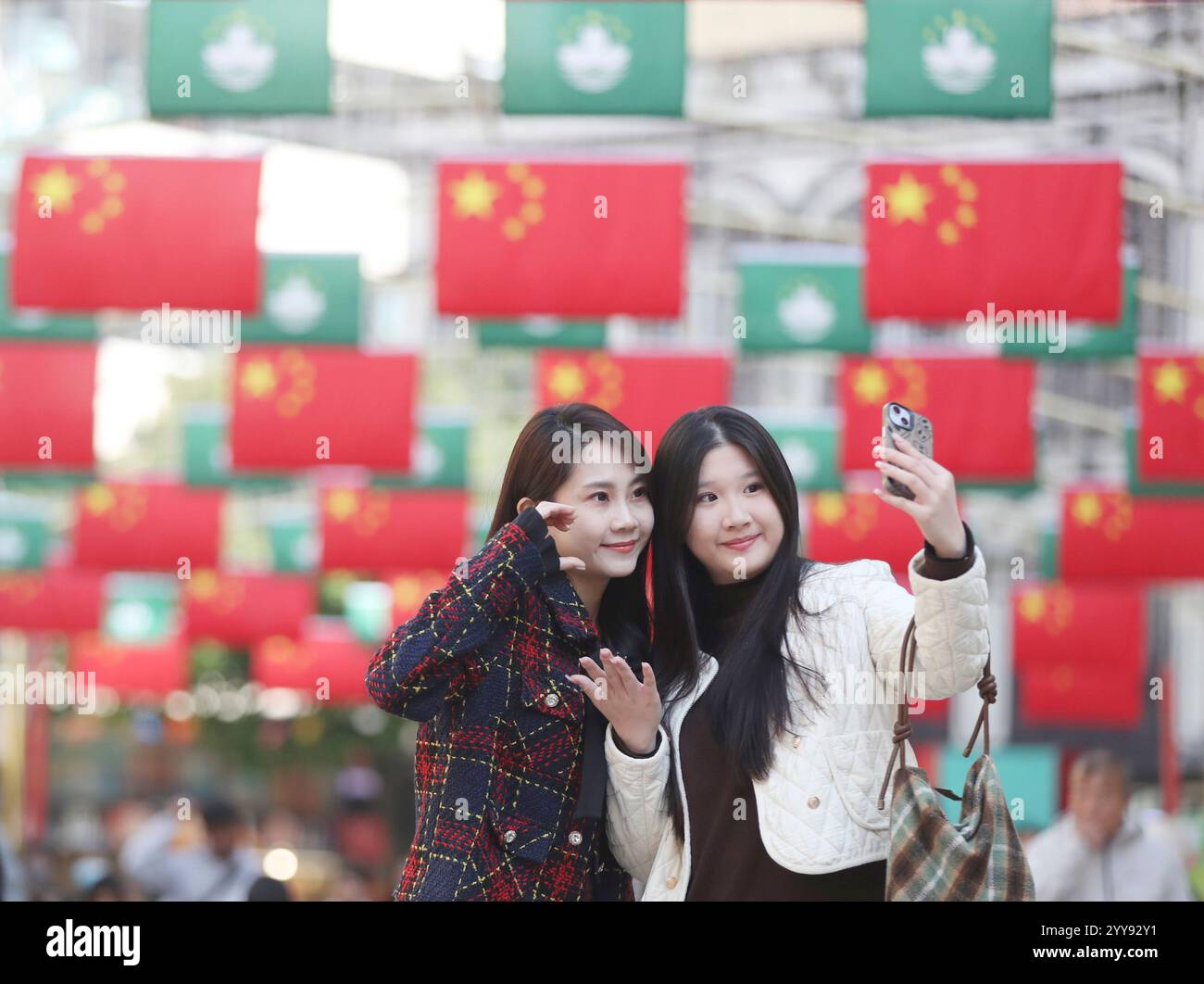 Macao. 20th Dec, 2024. People pose for photos at the Senado Square in ...
