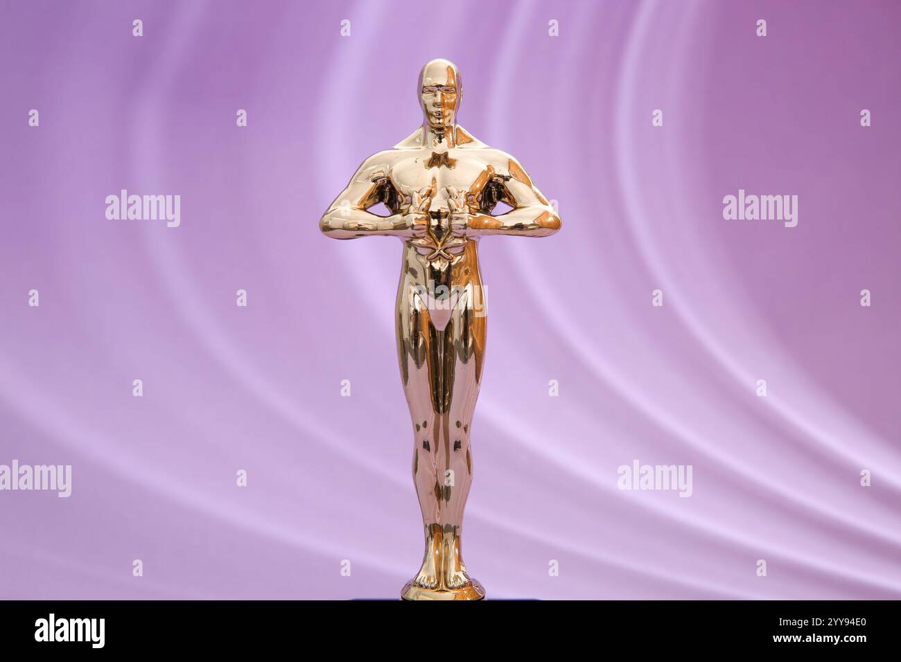 Golden trophy in shape of human figure on violet background Stock Photo ...