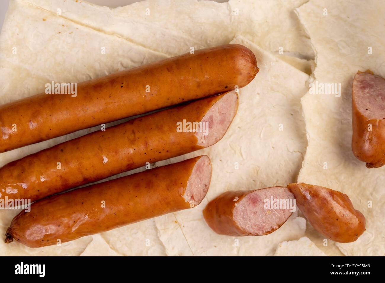 pork sausages on a wheat tortilla, closeup of thin pork sausages fried ...
