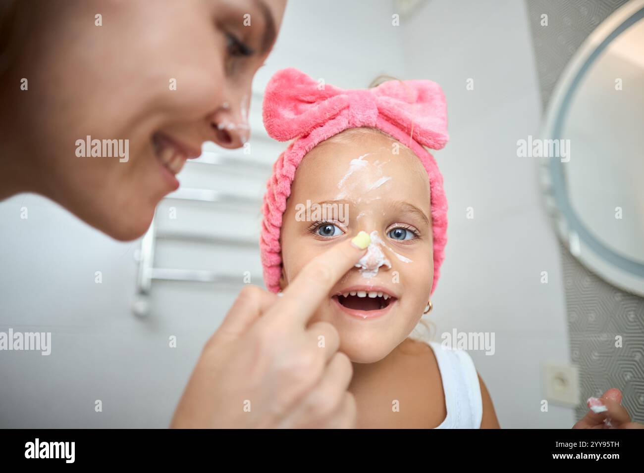 Smiling young woman and little daughter with a cosmetic bow on their ...
