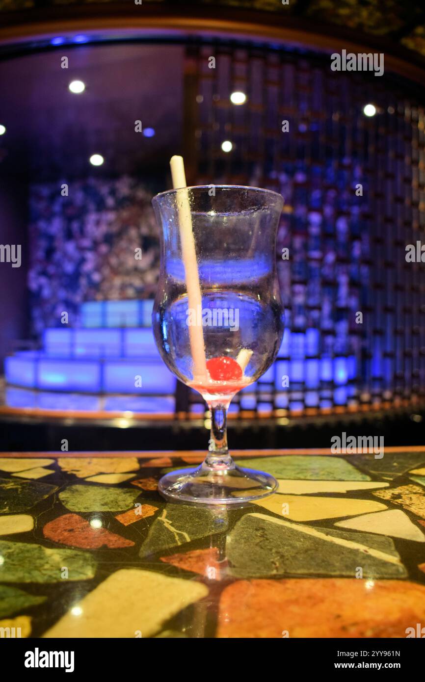 Cocktail glass emptied of beverage with cherry and biodegradable straw ...