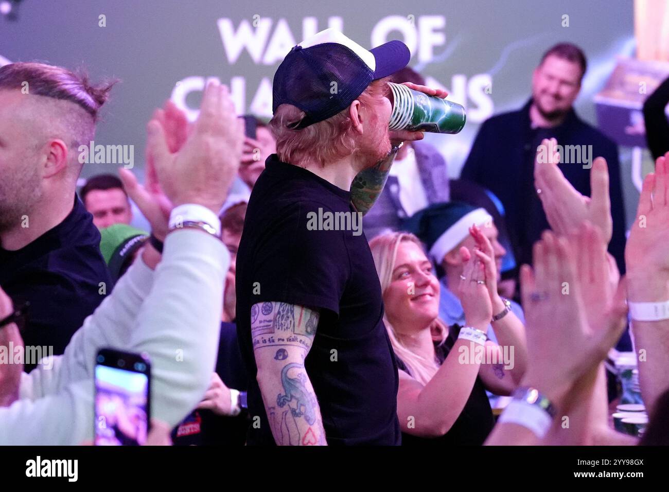 Singer songwriter Ed Sheeran drinks from a cup while being encouraged ...