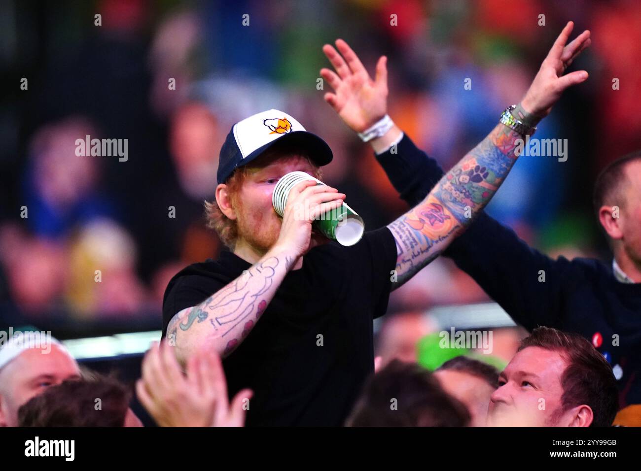 Singer songwriter Ed Sheeran drinks from a cup while being encouraged ...