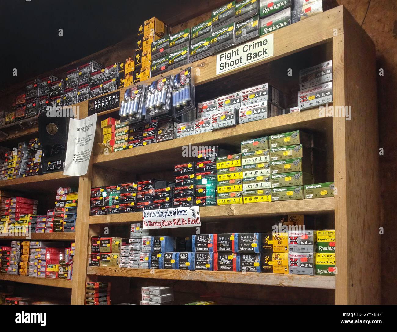 View through window of firearms shop at night with shelves of ...