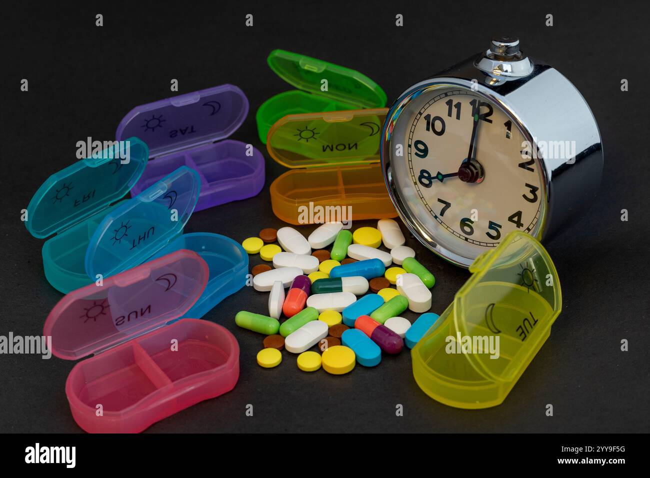 Pill organizer boxes and alarm clock with assorted pills. Timing and ...