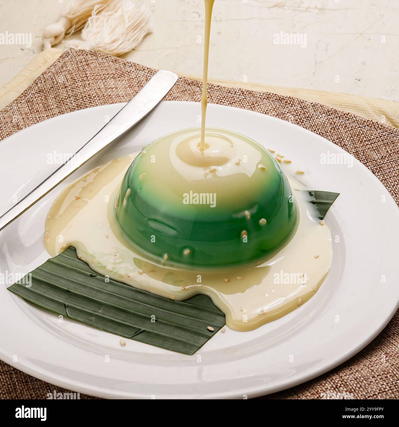 A beautifully presented green pandan jelly dessert topped with a silky ...