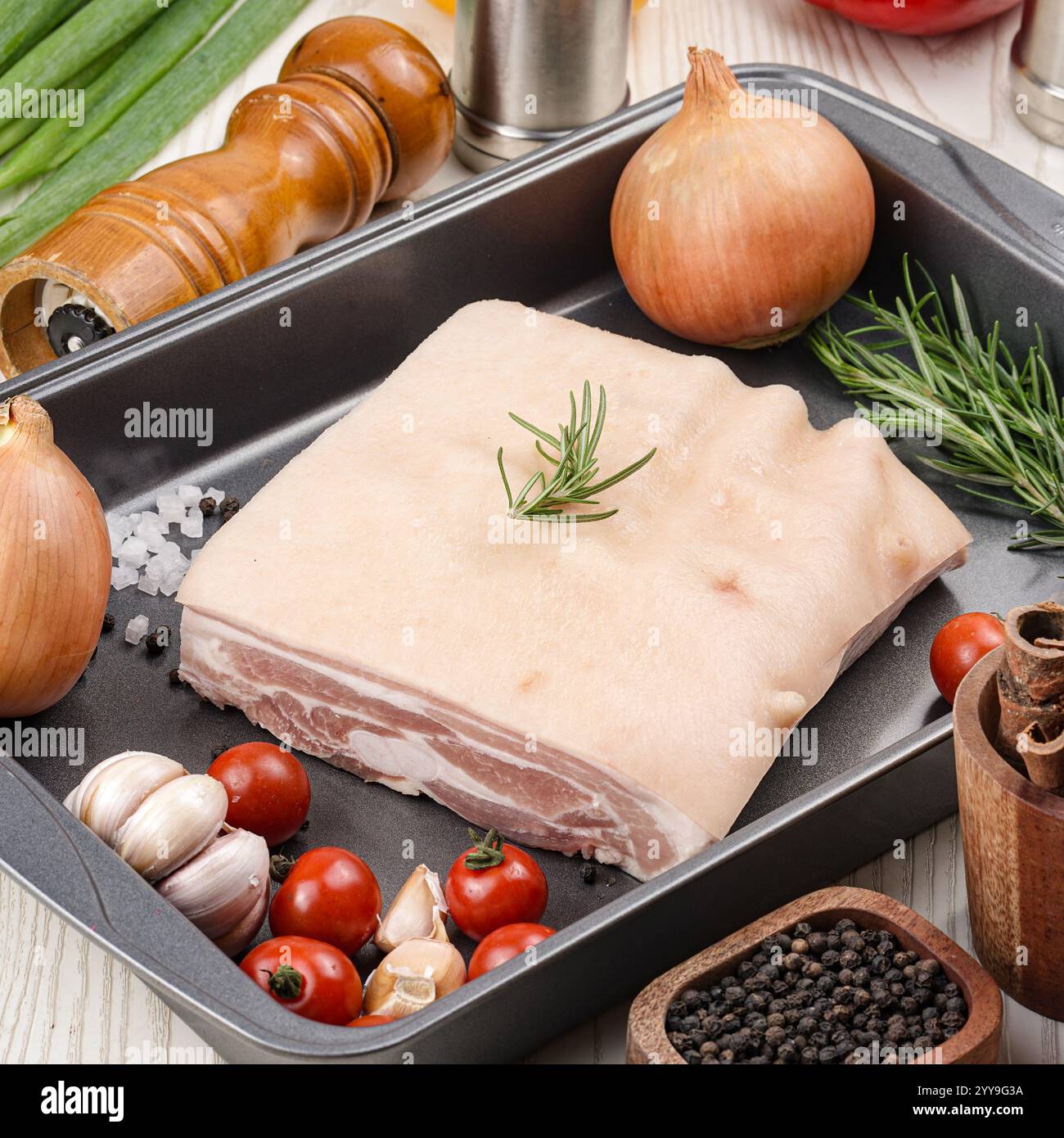 Fresh raw pork belly slab with skin-on, garnished with rosemary, cherry ...
