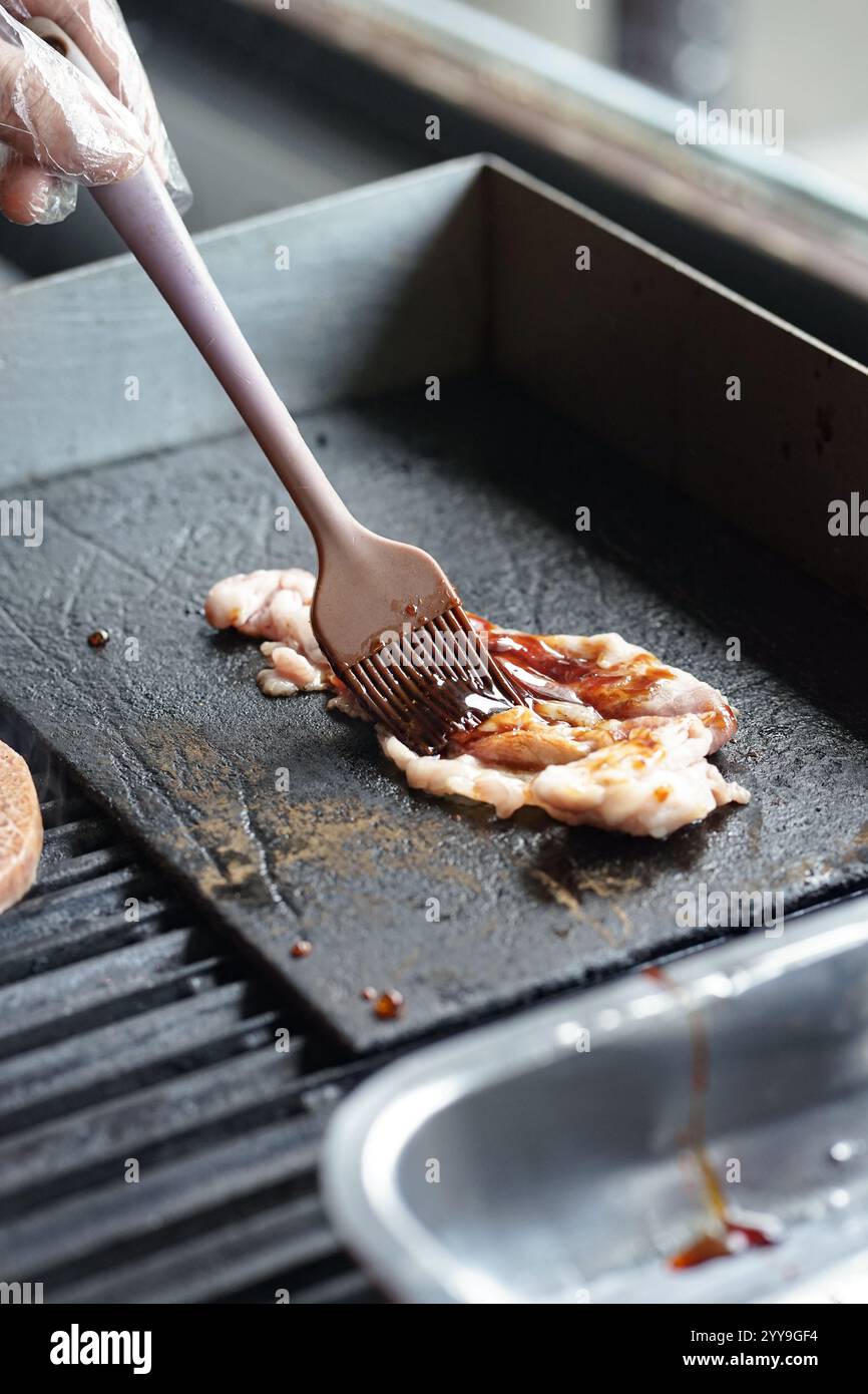 A close-up shot of grilled Korean BBQ beef being lifted with metal ...