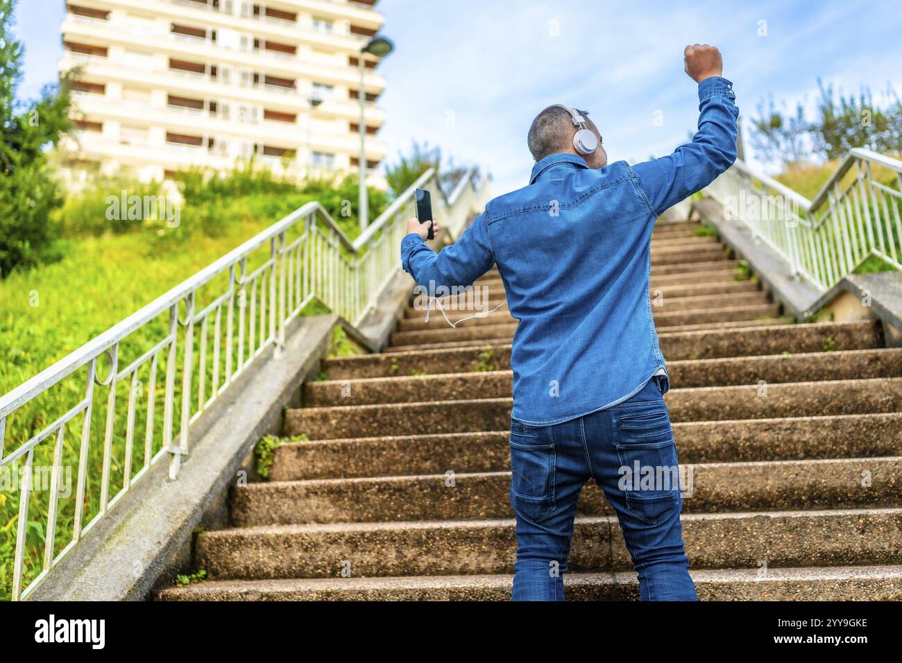 Rear view of a mature man dancing listening to music with mobile phone ...