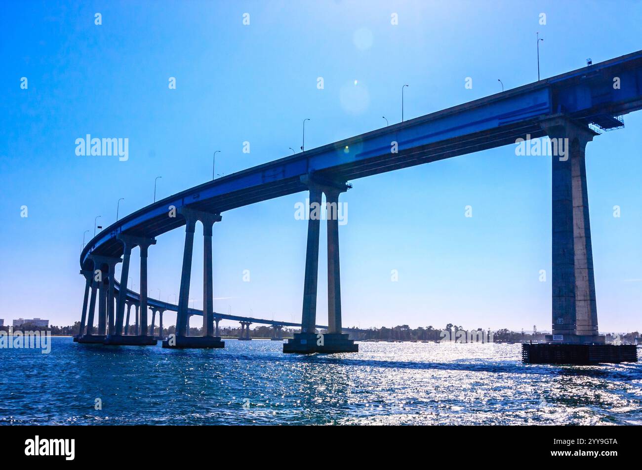A large bridge spans a body of water, with a clear blue sky above. The ...