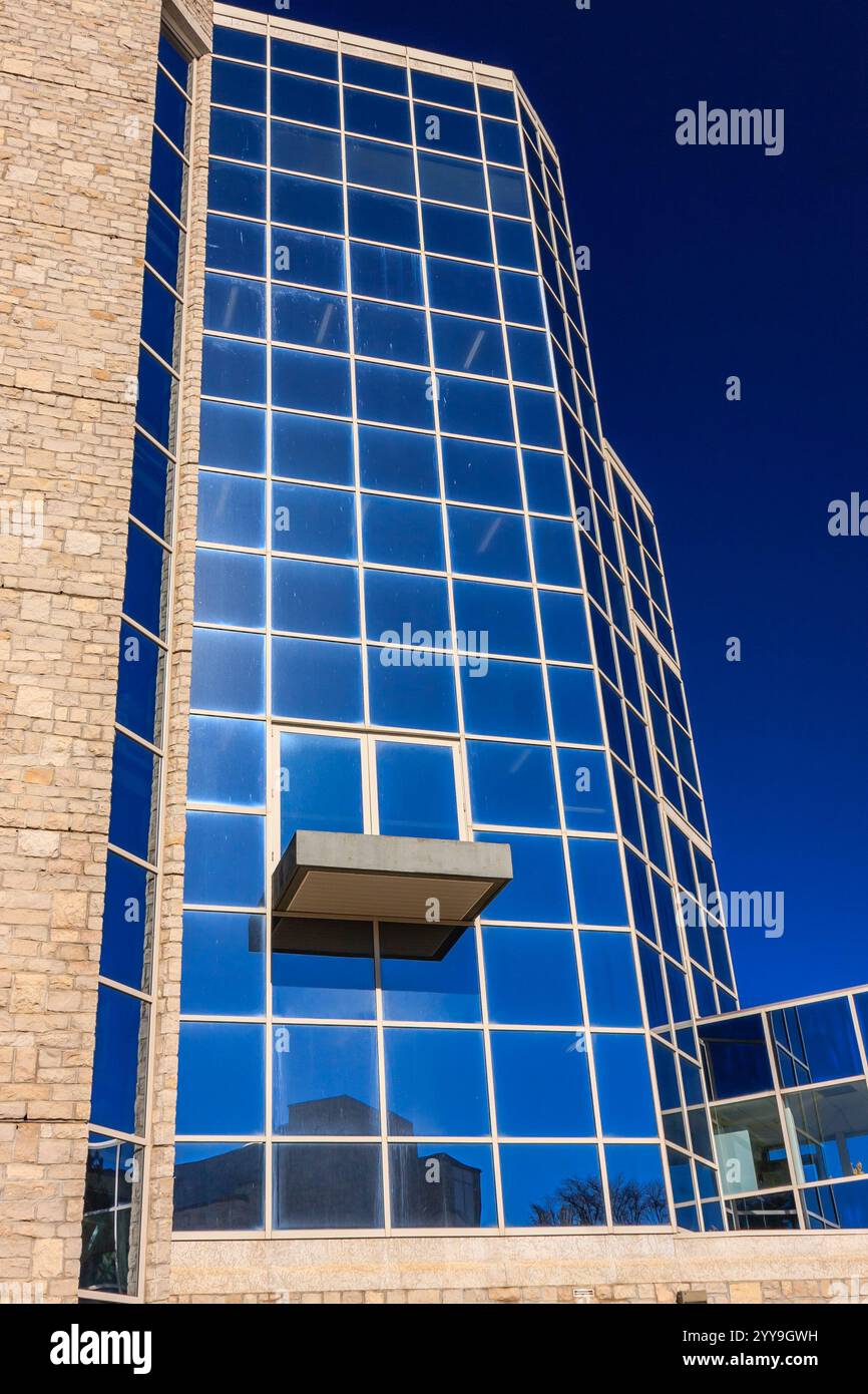 A tall building with a glass facade and a balcony. The glass is ...