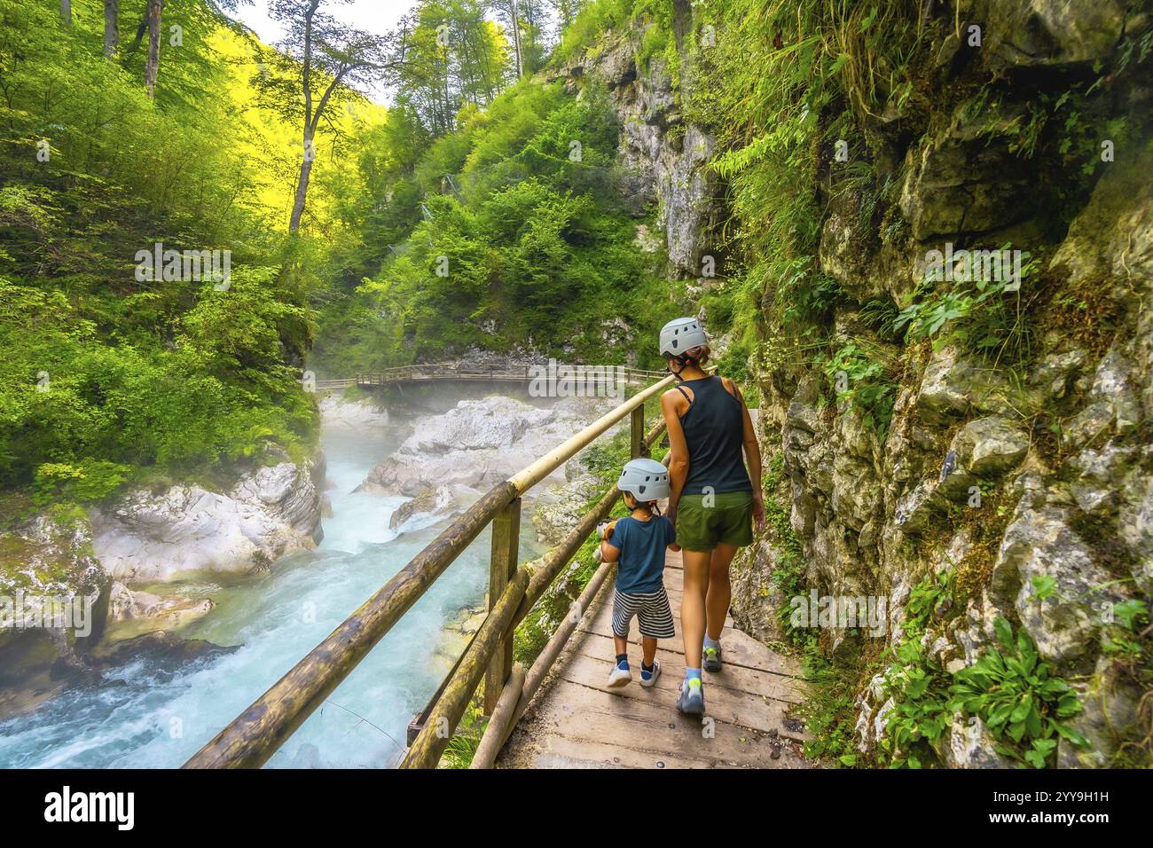 Mother and son wearing helmets walking on wooden path and enjoying ...