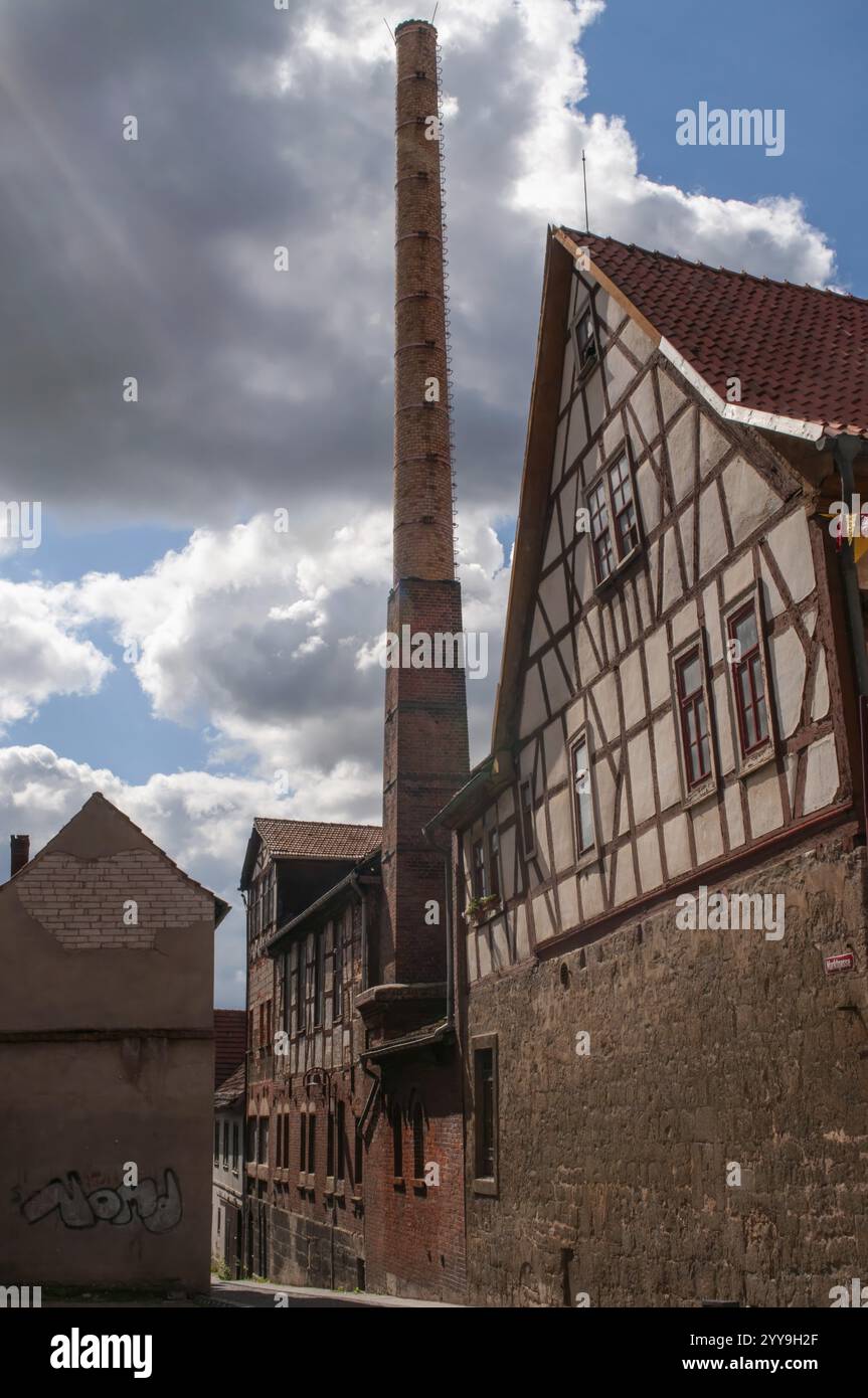 Tall industrial chimney rises above traditional half-timbered houses ...