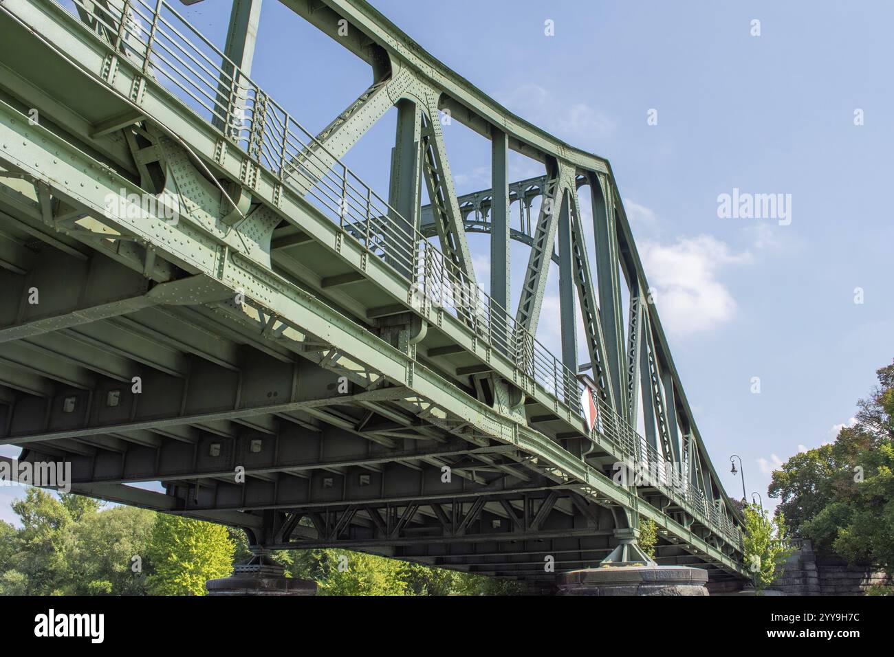 Low angle view of a green steel bridge spanning across a river ...